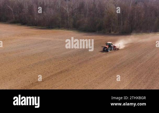 Tractor sowing seeds with a seeder driller in a field. Top view of ...