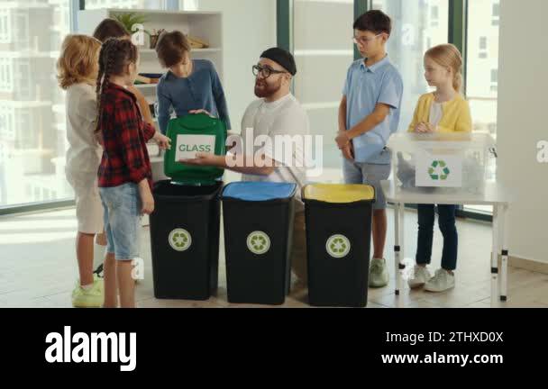 Garbage sorting class, a young teacher tells and explains to children ...