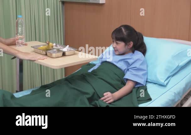 Nurse or doctor serving food with children girl patient at hospital ward, child eating food for ...