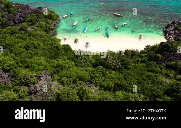 Sandy beach with tourists and tropical island by atoll with coral reef ...
