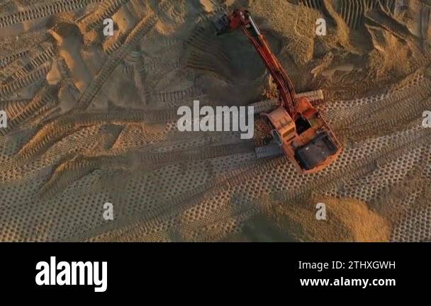 Excavator at work leveling the surface with sand at a construction site ...