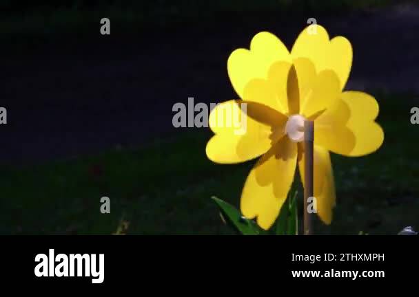 Shiny vibrant yellow wind mill pinwheel whiligig rotating in summer ...