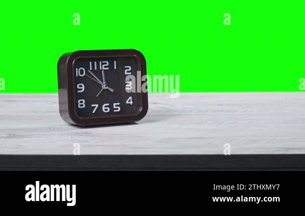 Analog clock on wooden table show time on green screen. The second-hand ...