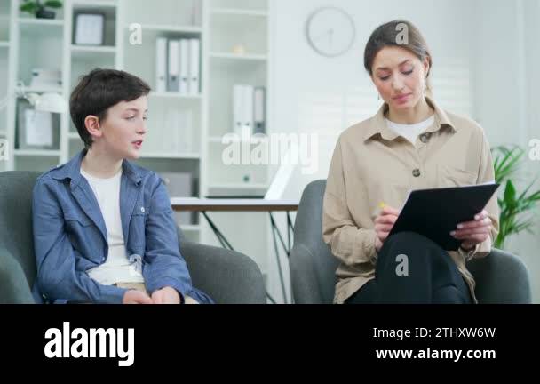 A female professional doctor child psychologist talks to a teenage boy ...
