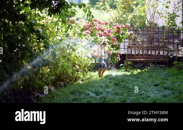 Splashing water into little boy outside in home garden during hot ...