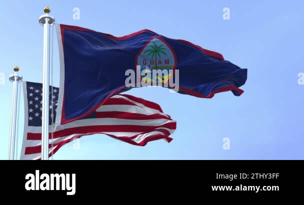 Flag of Guam waving in the wind with the US flag. Guam is an organized ...