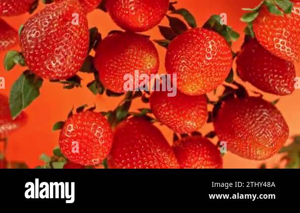 Super slow motion of rotating strawberries on red background, top view ...