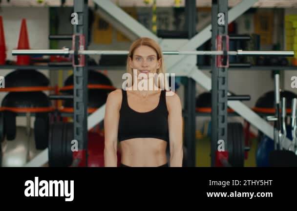 Biceps workout. Close up portrait of positive middle aged woman lifting dumbbells, training hand ...
