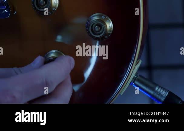 Adjusting tone knobs and volume of electric guitar, close up. Vertical ...