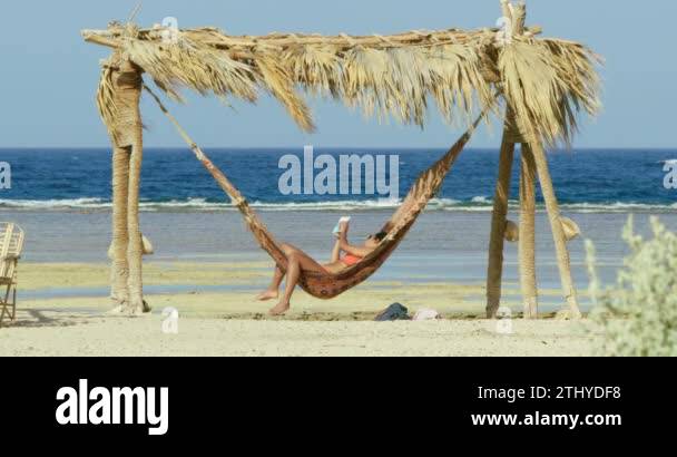 Woman wearing a bikini and reading a book on the beach, the woman is ...