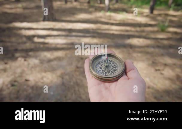Man holds a magnetic compass in his hands and looks for direction in ...