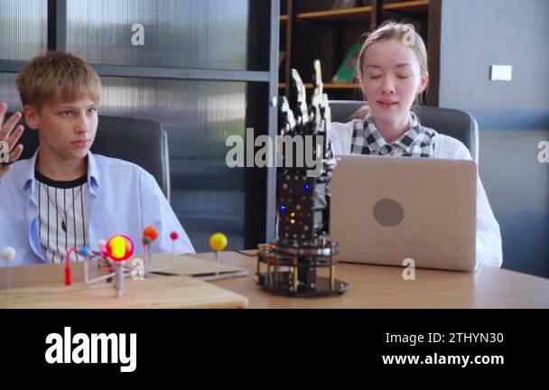 Caucasian two teenager students learning robotic arm in classroom ...