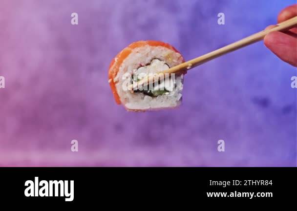 Take and hold one sushi roll using sticks for sushi, close-up. A human ...