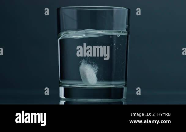 Closeup tablet dropped glass at dark background. Effervescent pill ...