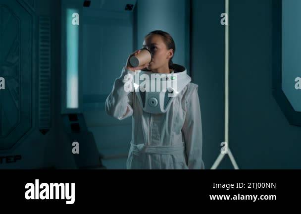 Girl space tourist drinking coffee aboard a spaceship. Attractive Asian ...