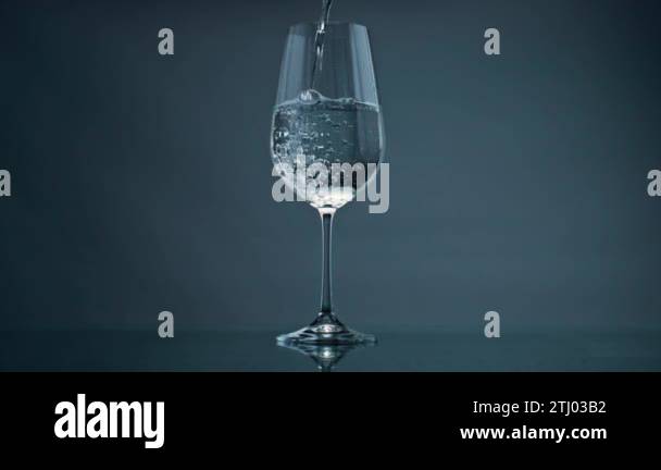 Pure water filling glass at dark background closeup. Bubbles rising ...