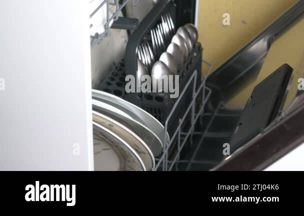 Man loading dirty dishware and other kitchen utensils, pushing it ...