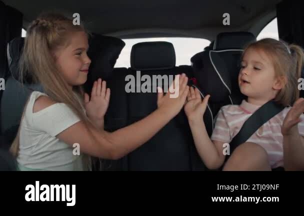Two caucasian female children sitting on the back seat and playing ...