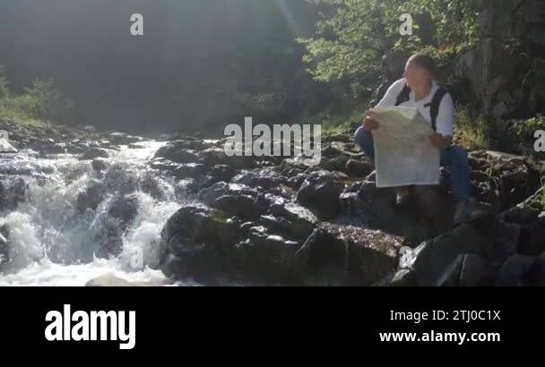 The thoughtful lost hiker man is looking for the way using paper map ...