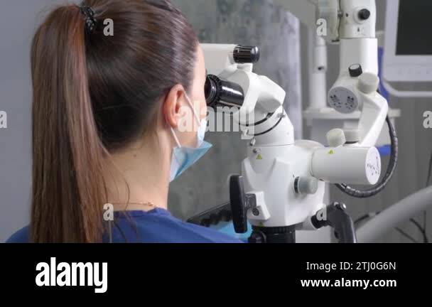 Female dentist using dental microscope treating patient teeth dental ...