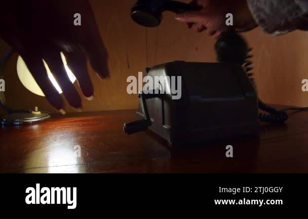 Hand turns the crank on the phone to make the connection. Quick action ...