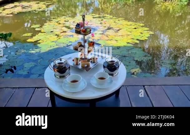 Afternoon tea at a water pond, high tea in a tropical garden in ...
