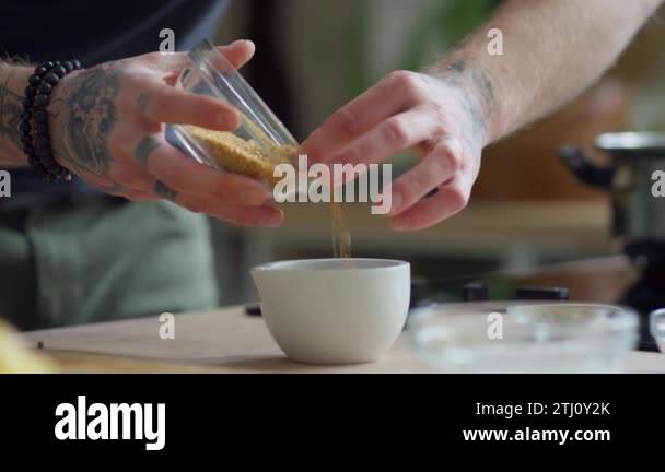 Tilt up shot of bearded chef adding toasted sesame seeds into mortar ...