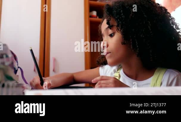 Mixed race girl writing notes doing homework at home. Little girl kid ...