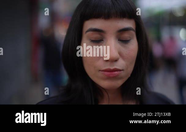 Contemplative young hispanic woman closing eyes in street. South ...