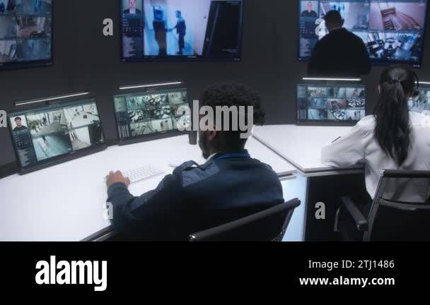 Multi ethnic security officers control CCTV cameras with AI facial ...