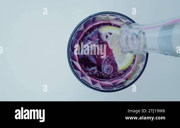 Close up of pouring water with gas from a bottle into a glass with ice ...