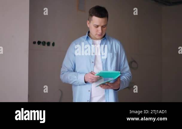 Thoughtful man with digital tablet standing in new apartment looking ...
