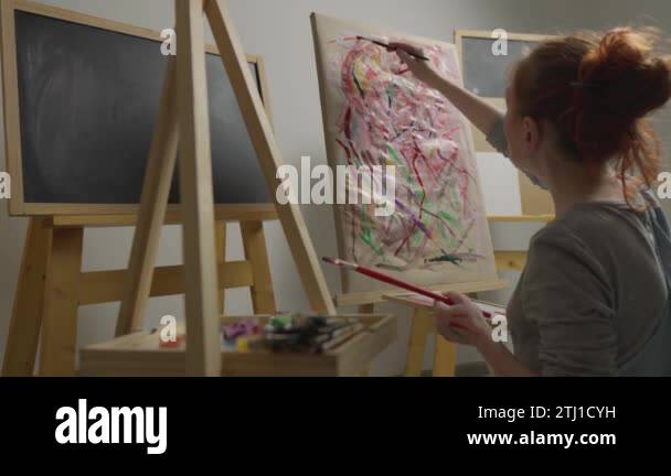 The artist in the photo focuses on drawing her works of art on an easel ...