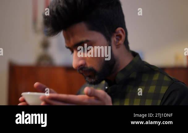 Side view satisfied young Middle Eastern man smelling small plate in ...