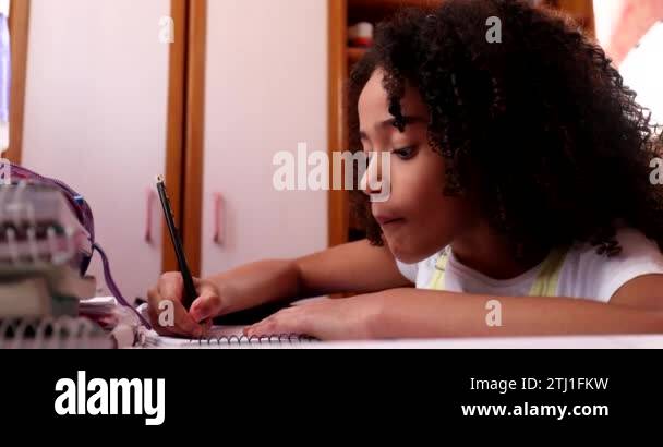Mixed race girl writing notes doing homework at home. Little girl kid ...