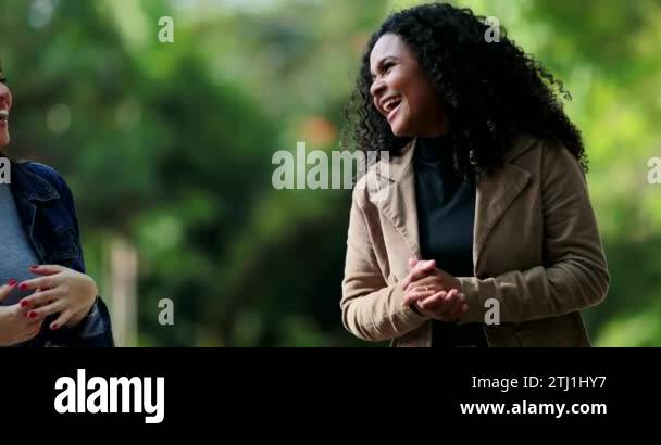 Two candid women laughing and smiling together outside, real life laugh ...