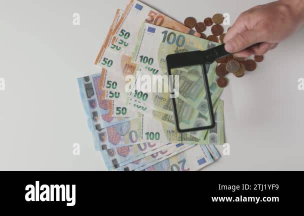 Checking counterfeit money with magnifying glass. Checking euro ...