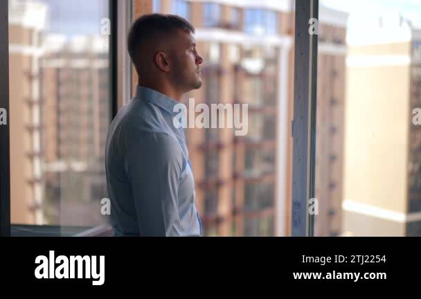 Caucasian young man looking out the window crossing hands smiling ...