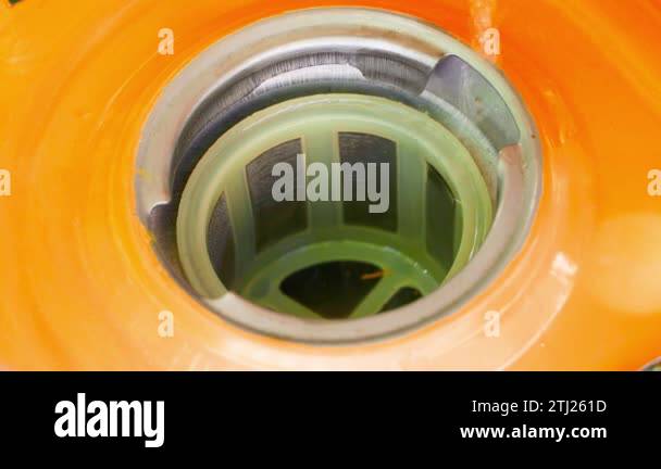 Fuel is poured into the fuel tank of a yellow gas generator from a ...