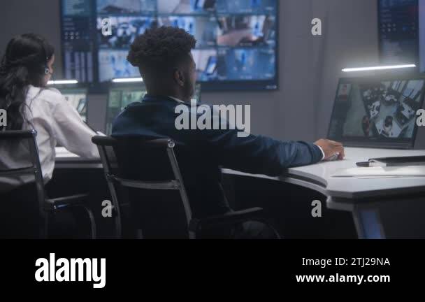 African American security operator monitors CCTV cameras with AI face ...