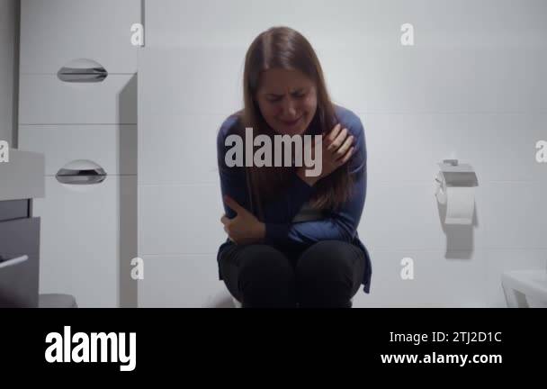 Portrait of woman suffering from depression crying on toilet at home ...