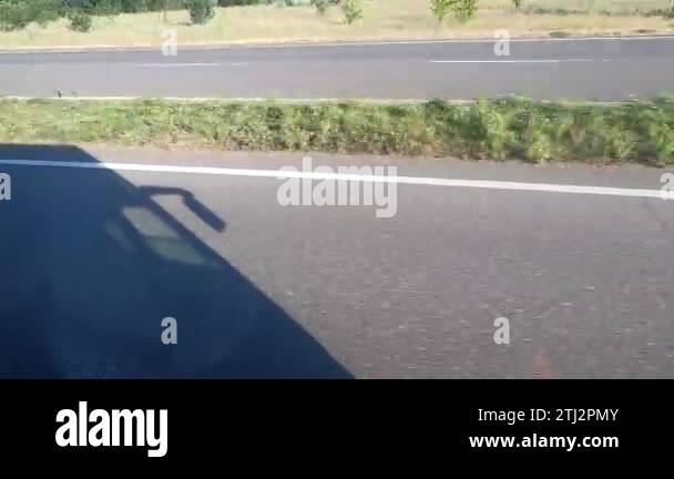 Shadow of the drivers cabin of a bus driving on an asphalt road. View ...