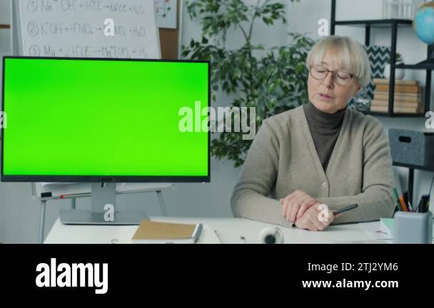 Online tutor pointing at computer with chroma key green screen teaching ...