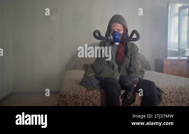 A woman in a gas mask sitting an post-apocalyptic building in smoke ...