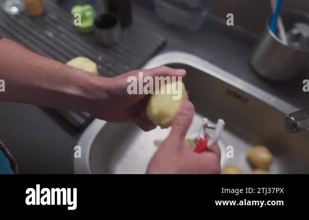 A man peels potatoes with a special vegetable peeler. Healthy food ...