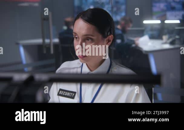 Female security operator in headset talks, controls CCTV cameras on PC ...