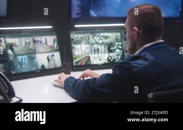 Male security operator controls CCTV cameras with AI face scanning and ...