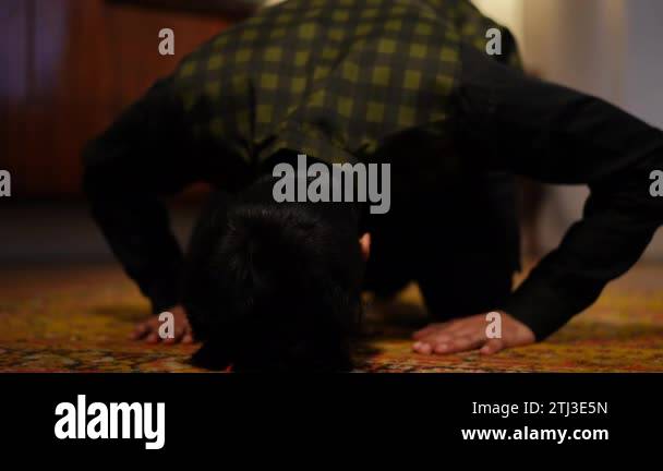 Close-up praying Muslim man bowing on carpet indoors. Unrecognizable ...