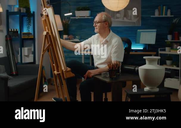 Portrait of retired man drawing professional artwork on canvas, using ...