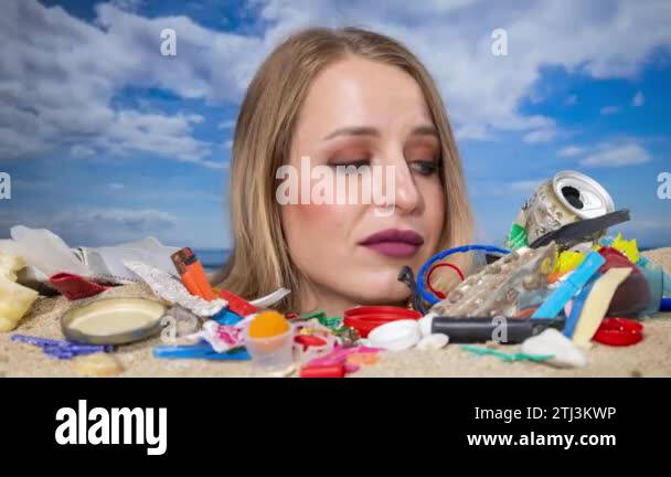 A pretty woman buried up to her head on a beach covered with trash and ...
